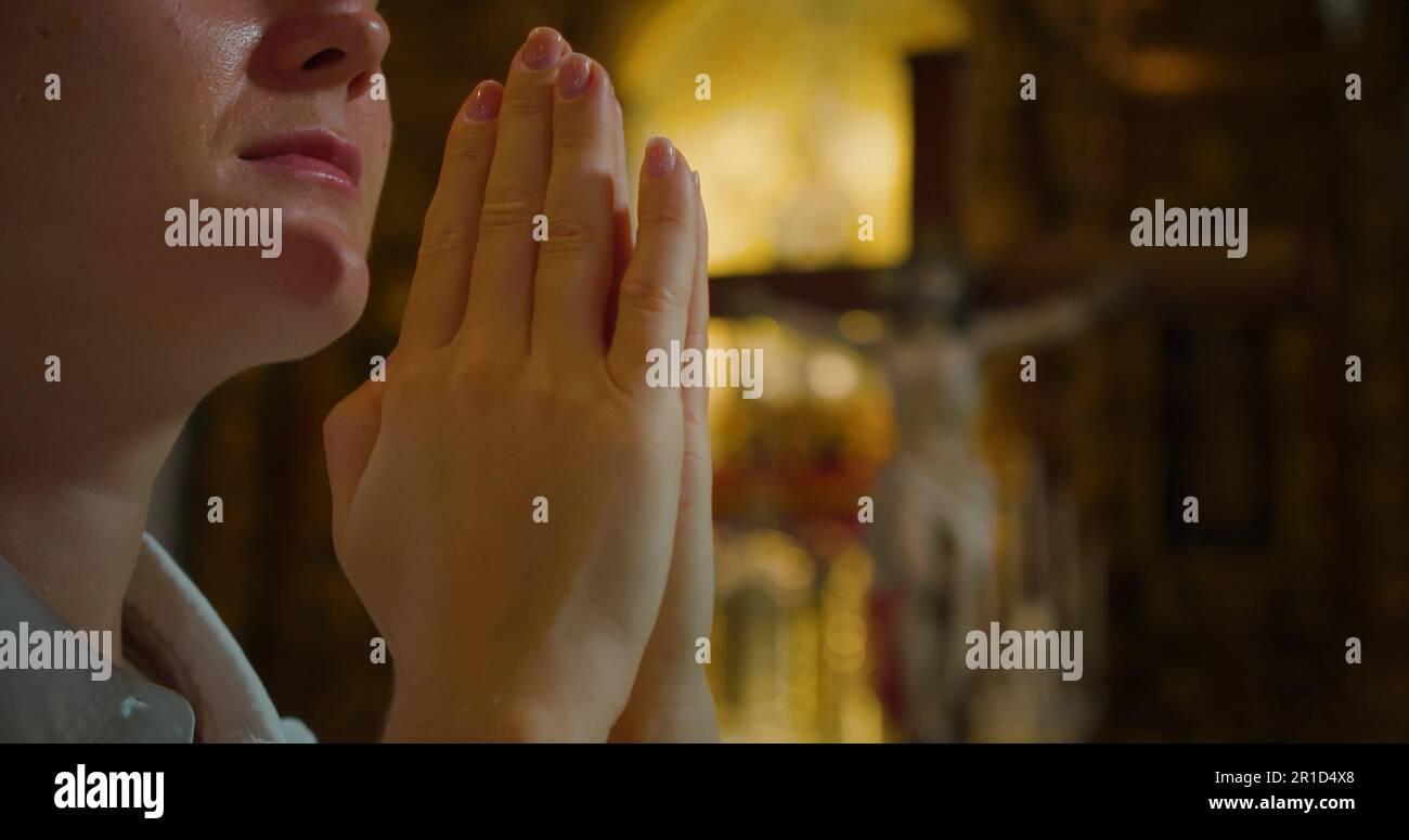 Christian woman folded hands in prayer in church. Close-up adult girl ...