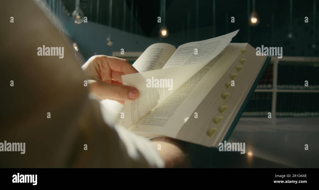 Female hands holding and reading a book in public library. Wooden book ...