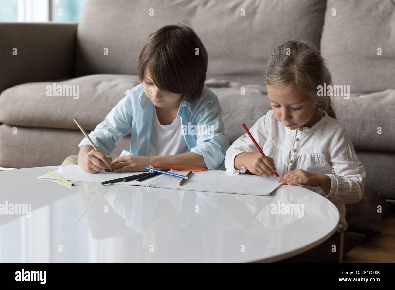 Serious cute little sibling children drawing in coloring pencils Stock ...