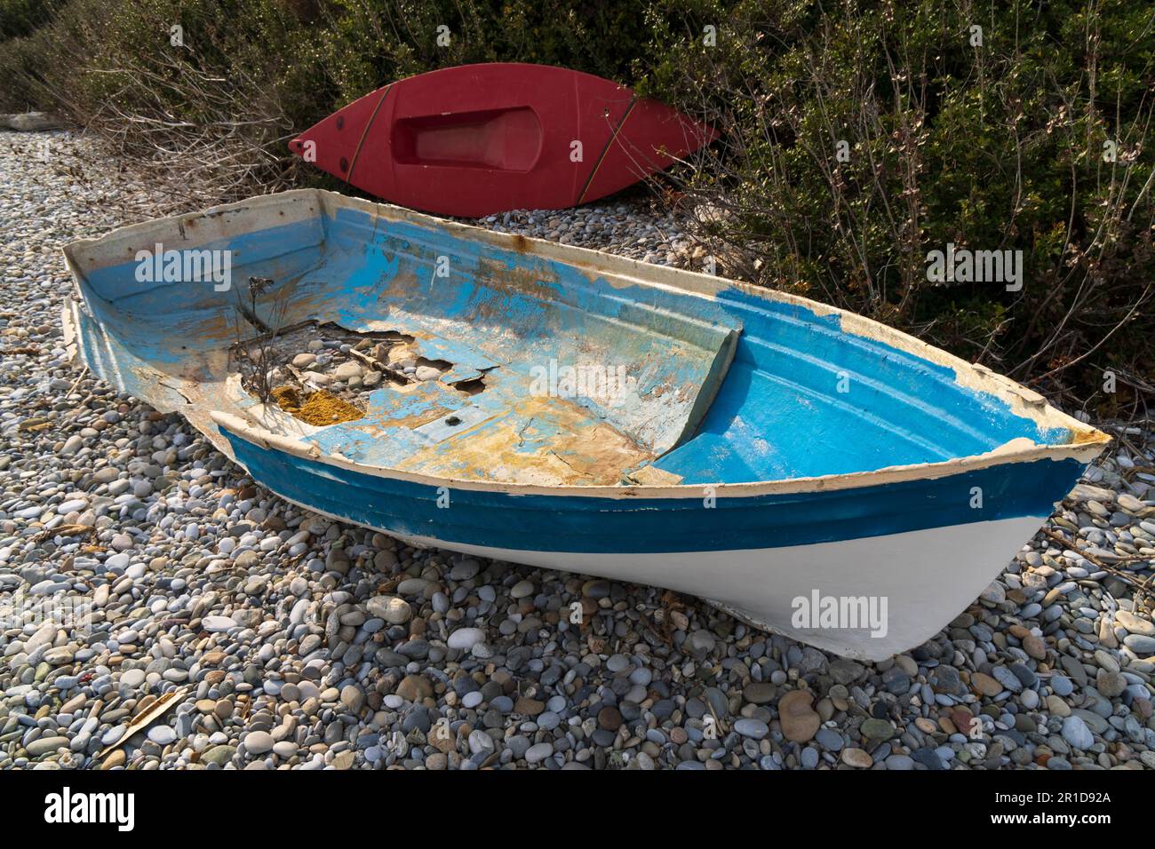 An abandoned broken boat full of holes lying on the seashore in the off season Stock Photo - Alamy