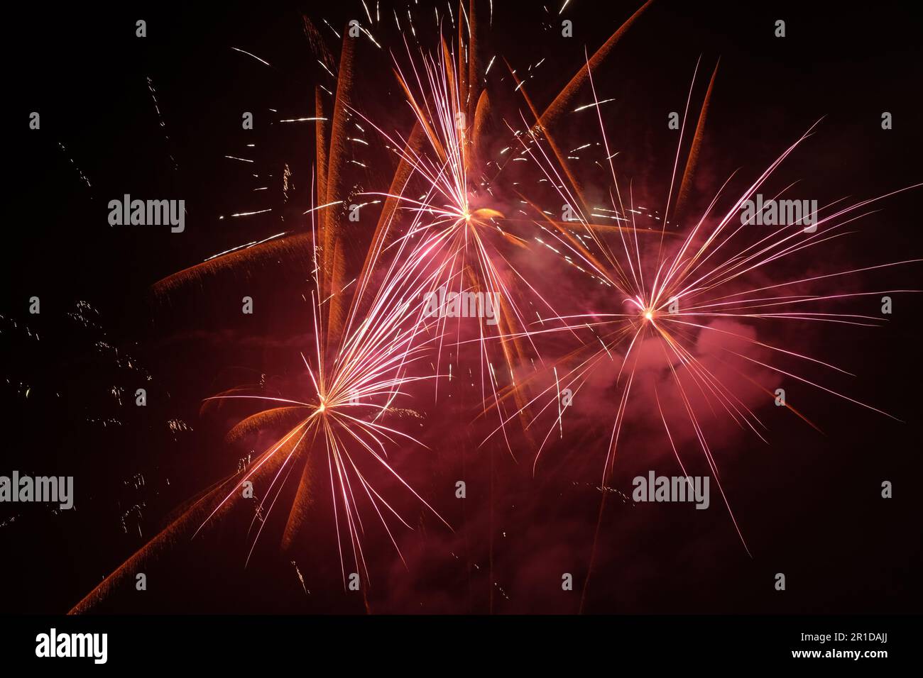 The three vibrant fireworks explosions with smoke and sparks in a night ...