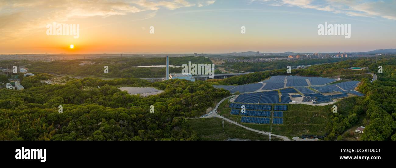 Panoramic aerial view of sunset on horizon and hilltop panels at solar ...