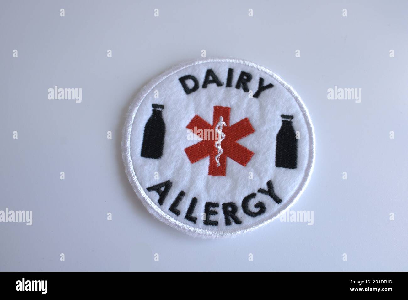 Dairy allergy sew on patch on a plain background. Lancashire, UK, 13-05 ...