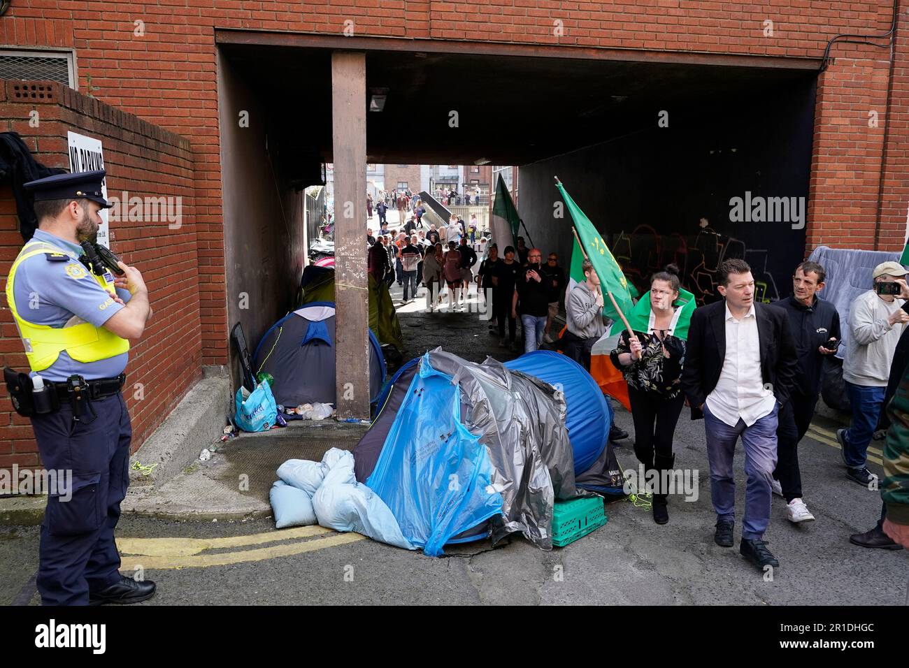 Protesters walk past tents of homeless people outside the International ...