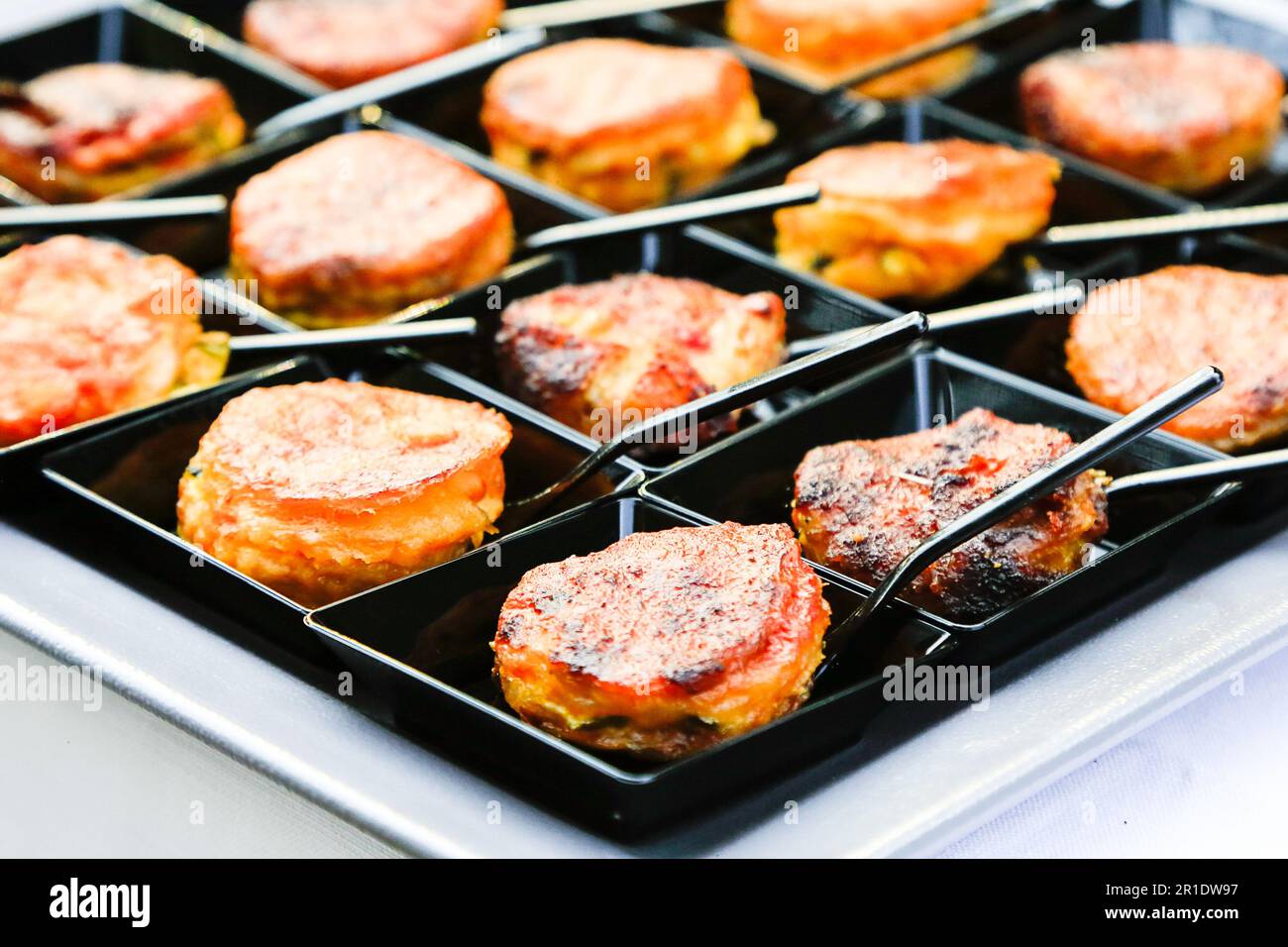 fingerfood closeup. small backed oriental snacks on square black plates ...