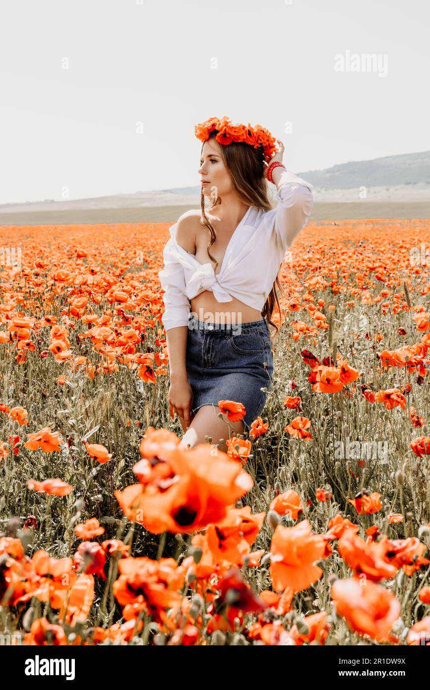 Happy woman in a poppy field in a white shirt and denim skirt with a ...