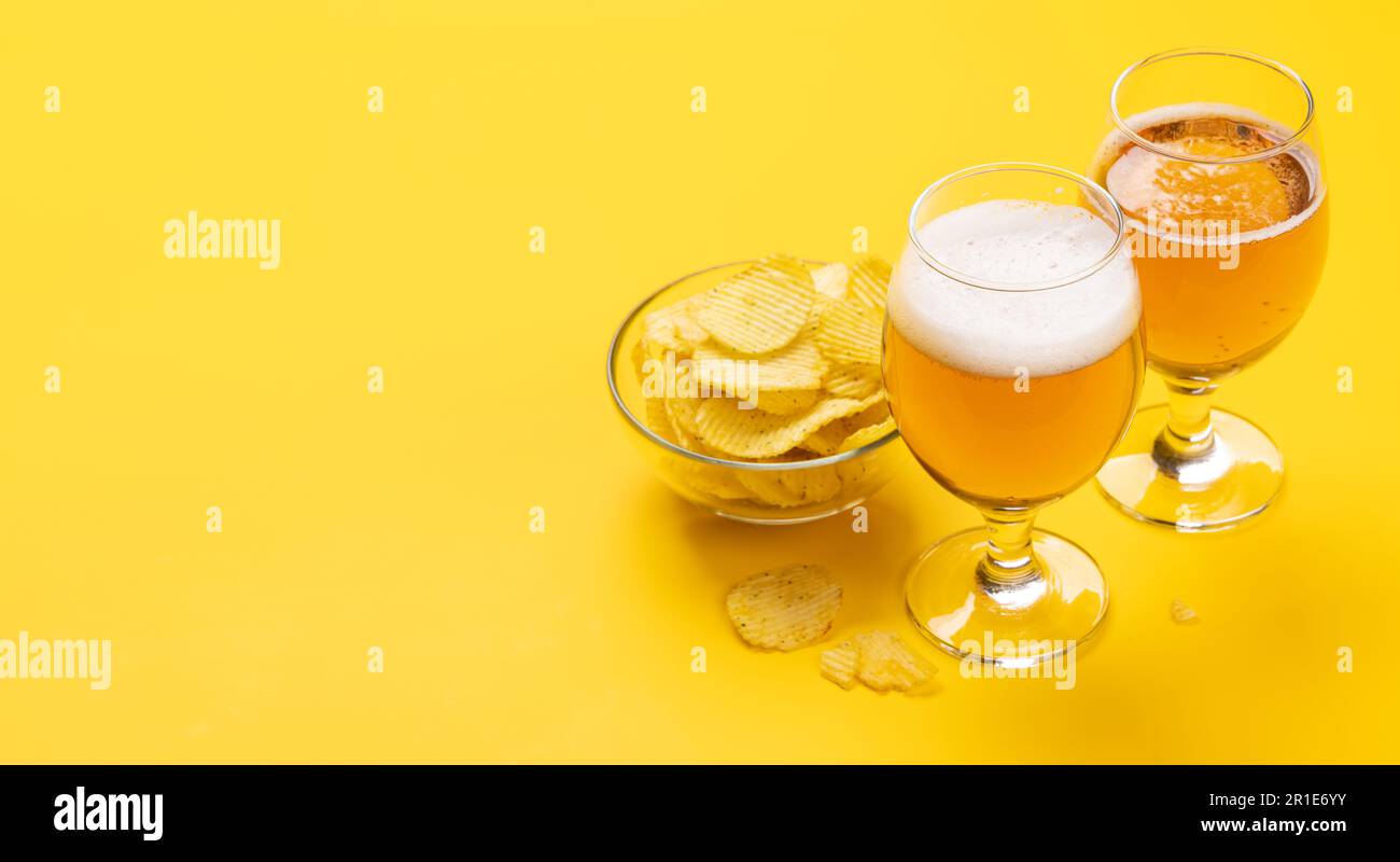 A tempting snack of beer and chips on a vibrant yellow background with ...