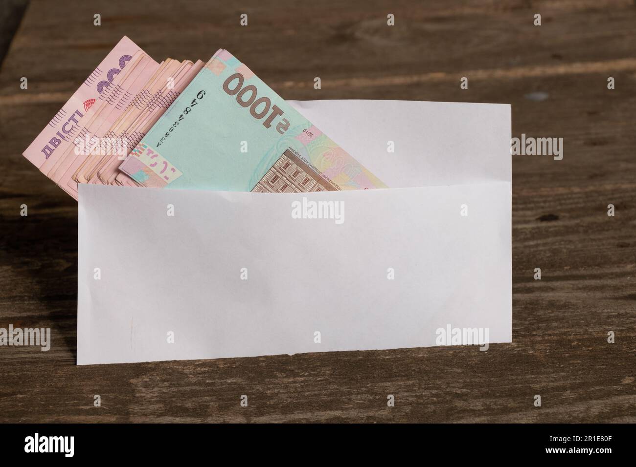 Ukrainian cash currency lies in a white envelope on an wooden table ...