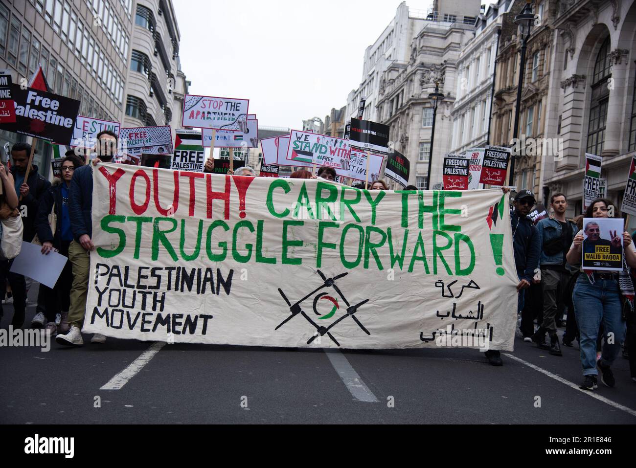 London, UK. 13th May, 2023. Protestors march with a large banner during ...