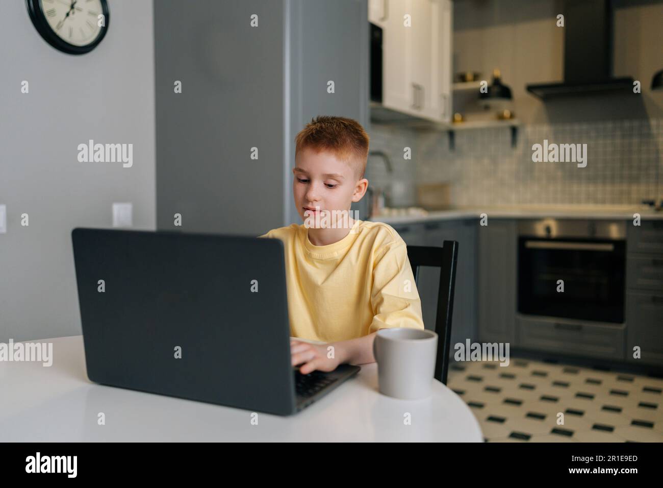 Portrait of adorable redhead child boy with freckles looking to laptop ...