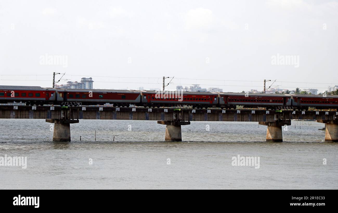indian railway train moving very quickly on a bridge over the river in ...