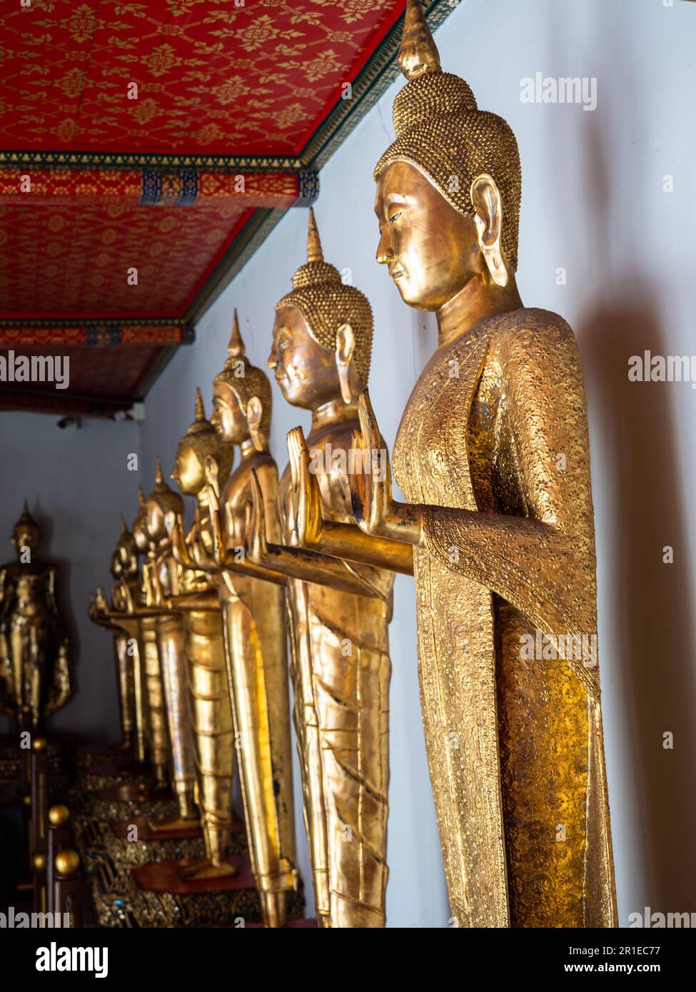 A row of standing golden Buddha statues line the wall of Wat Pho Temple ...