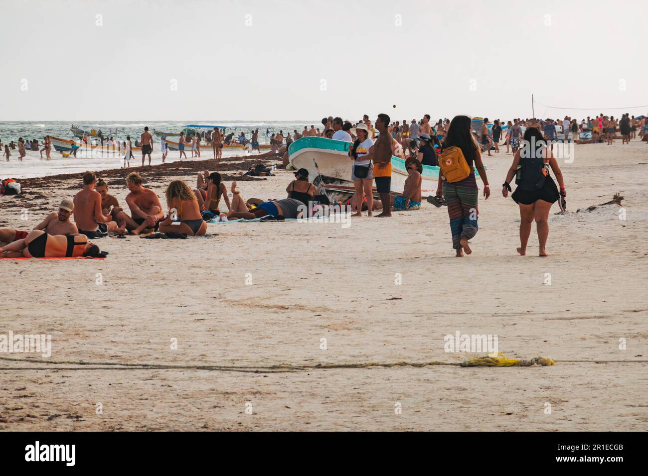 tourists and seaweed cover the beach in Tulum, Mexico. Sargassum algae ...