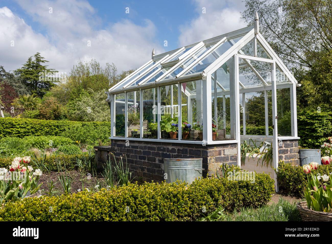 A garden plot with seedbeds and a glass greenhouse in the centre of ...
