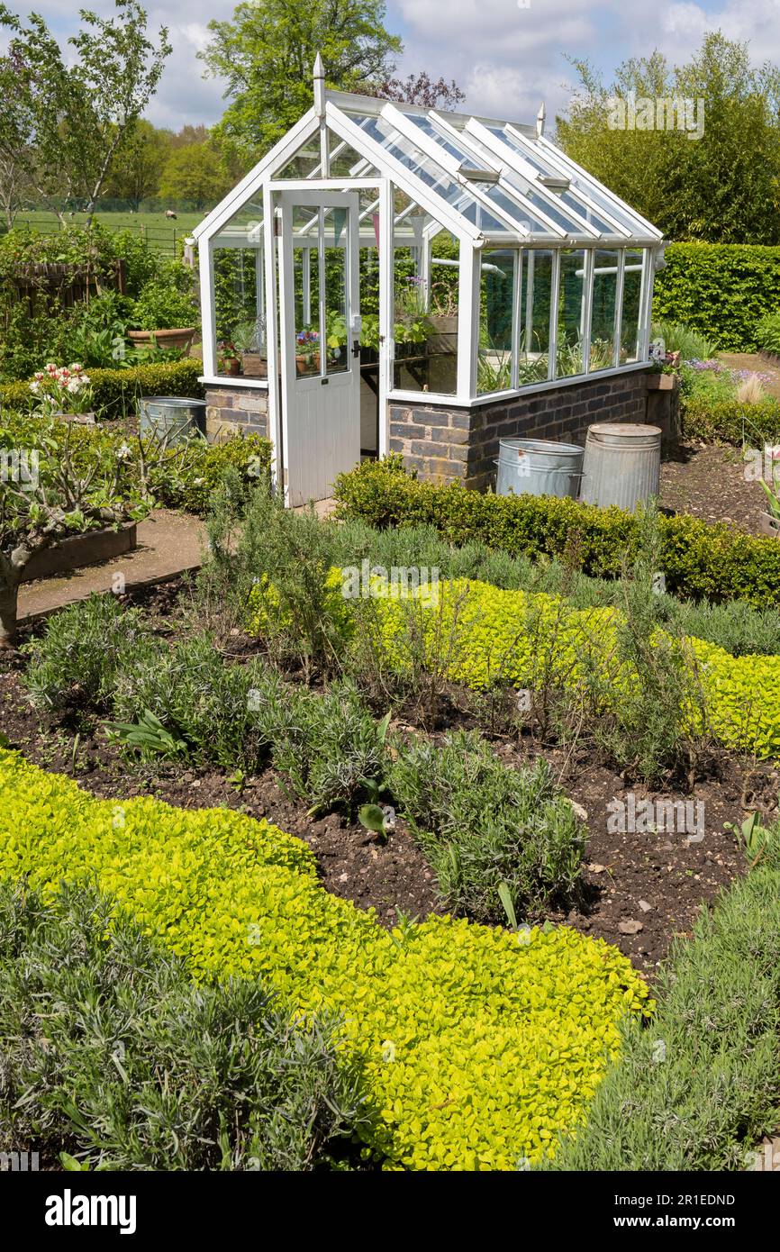 A garden plot with seedbeds and a glass greenhouse in the centre of ...