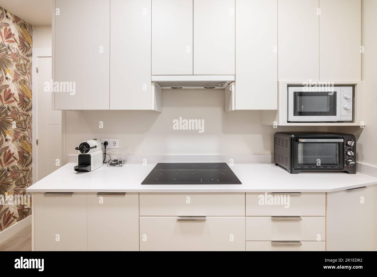Frontal shot of a white kitchen unit with functional appliances and a ...