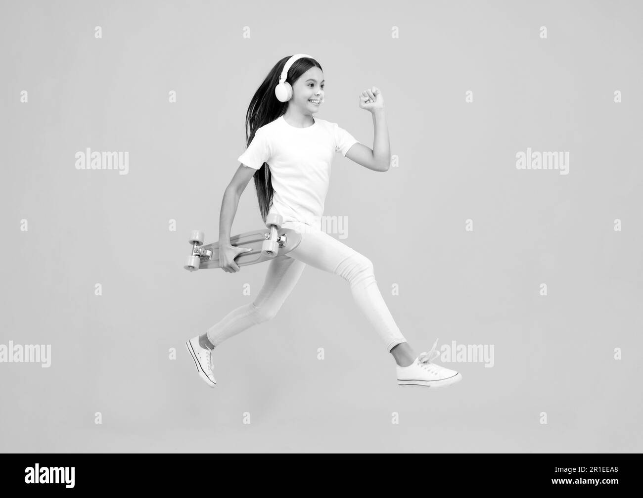 Teen girl 12, 13, 14 years old with skateboard over studio background ...