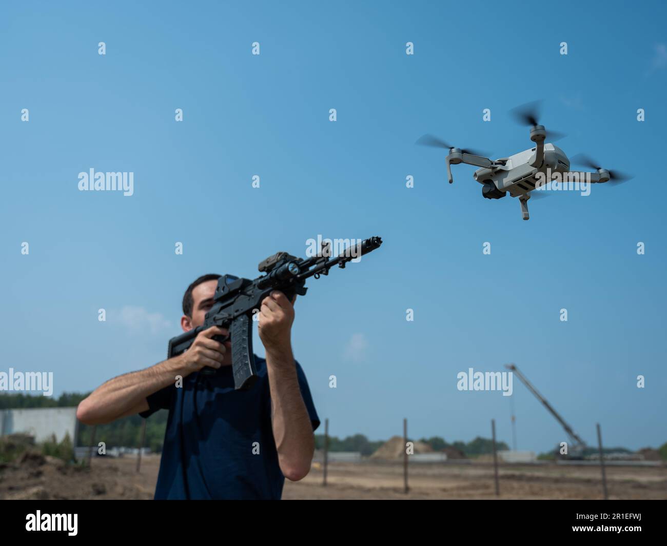 A man aims to shoot a rifle at a flying drone against a blue sky Stock ...