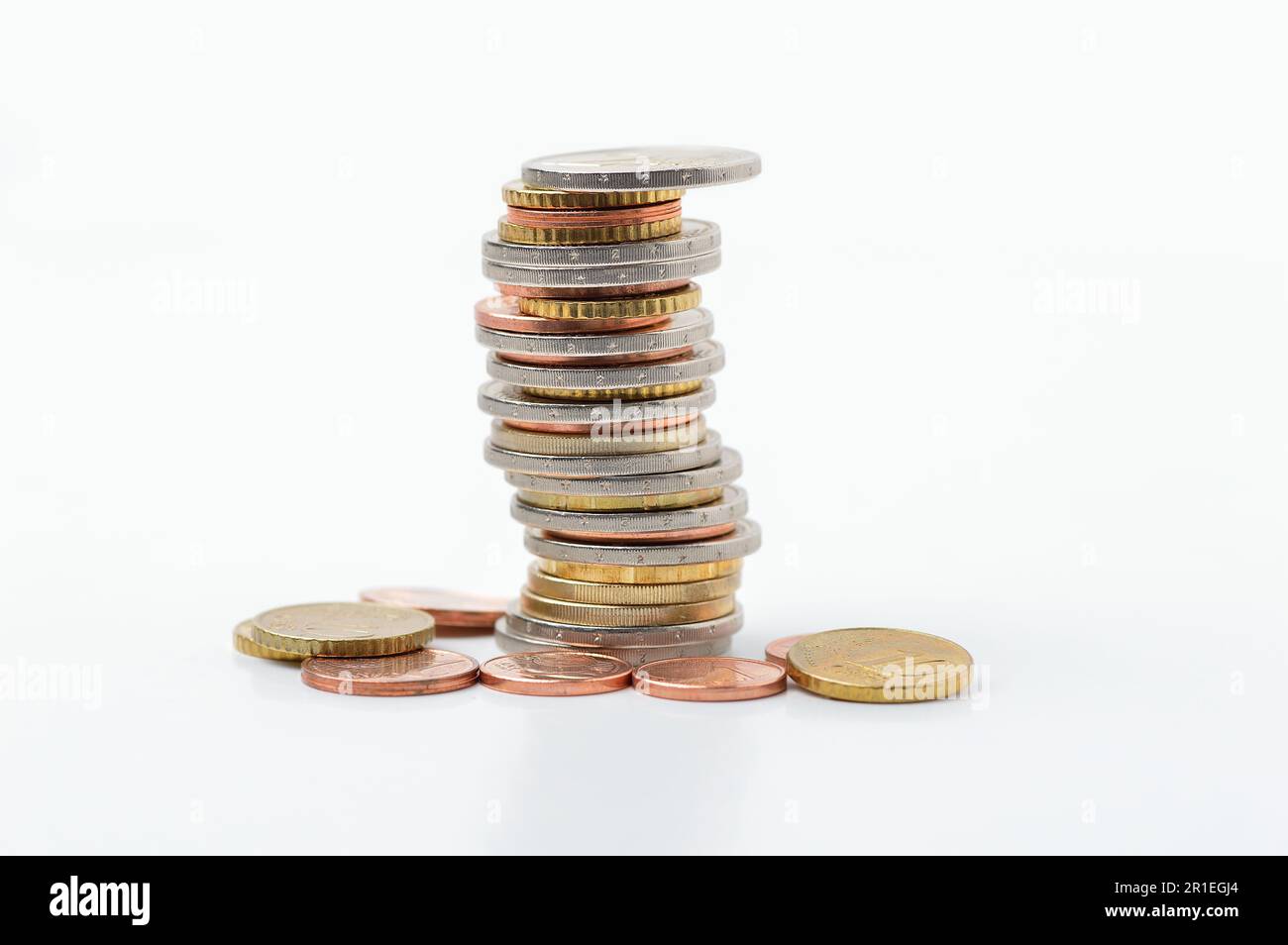 Many coins in column isolated on white Stock Photo - Alamy