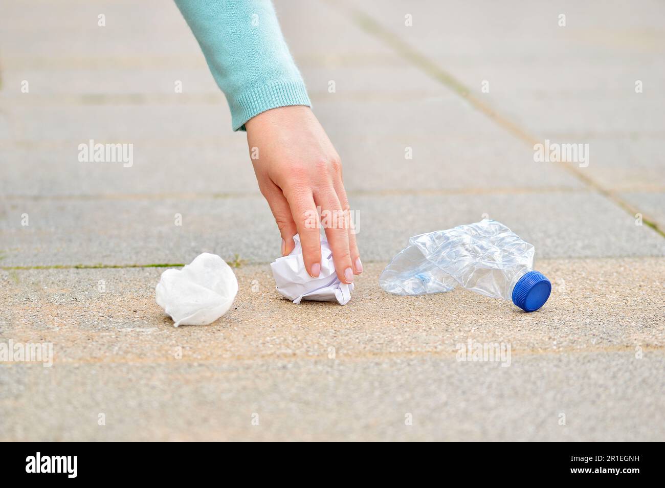 Close up of woman hand collecting garbage on the floor in the street ...