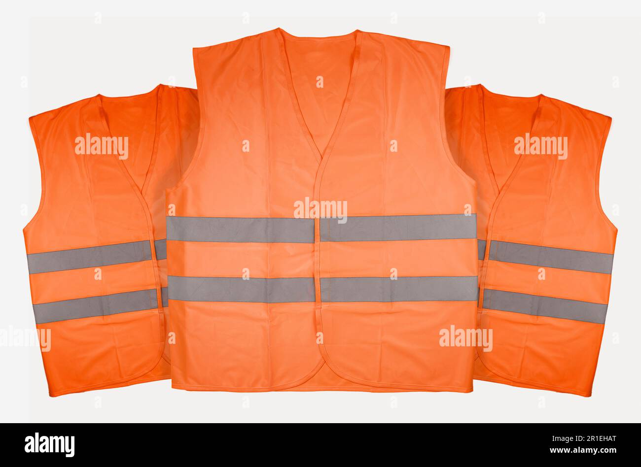 Three orange vests on white background Stock Photo - Alamy