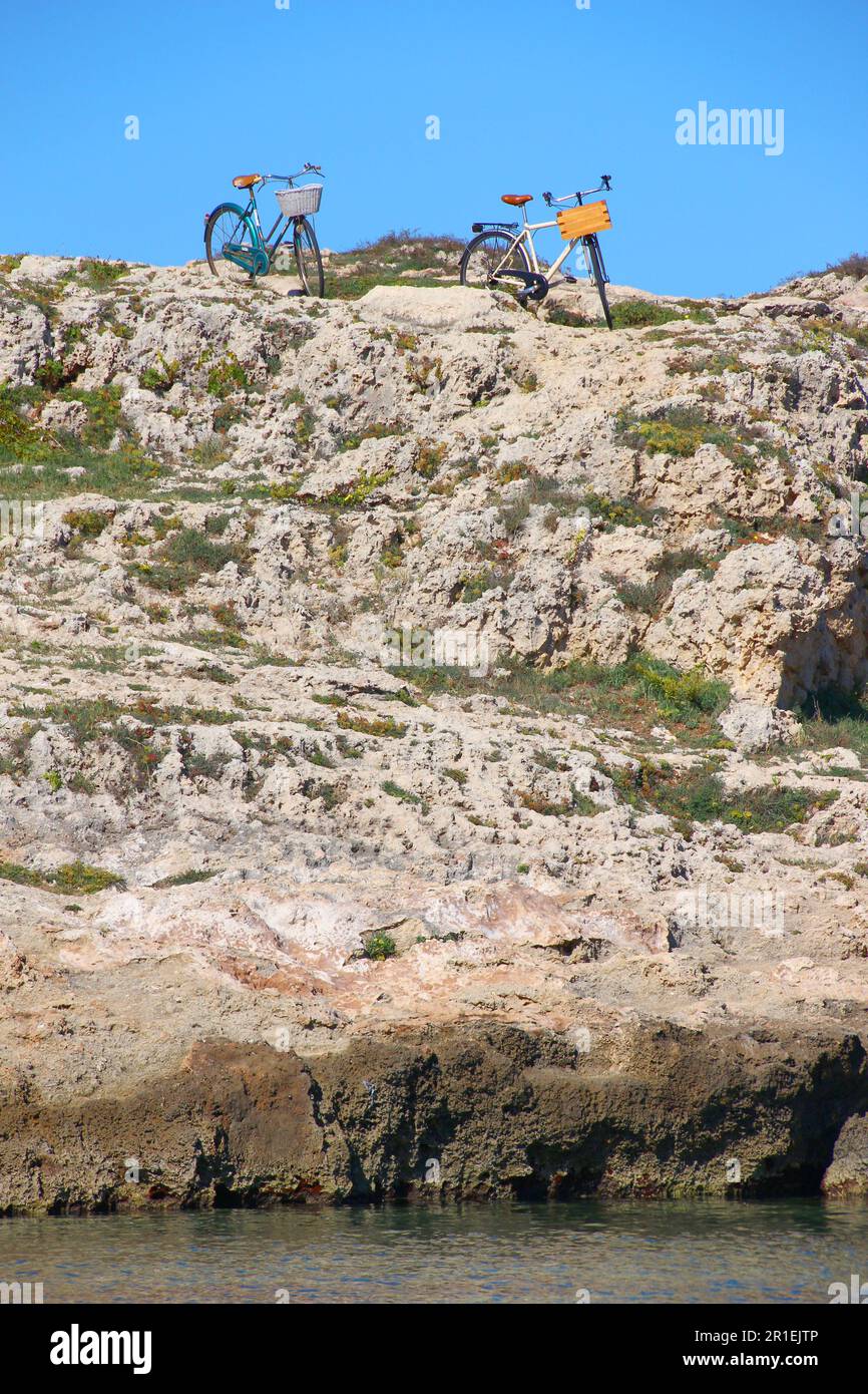 Colored retro bicycles resting on a light-colored stone and in the ...
