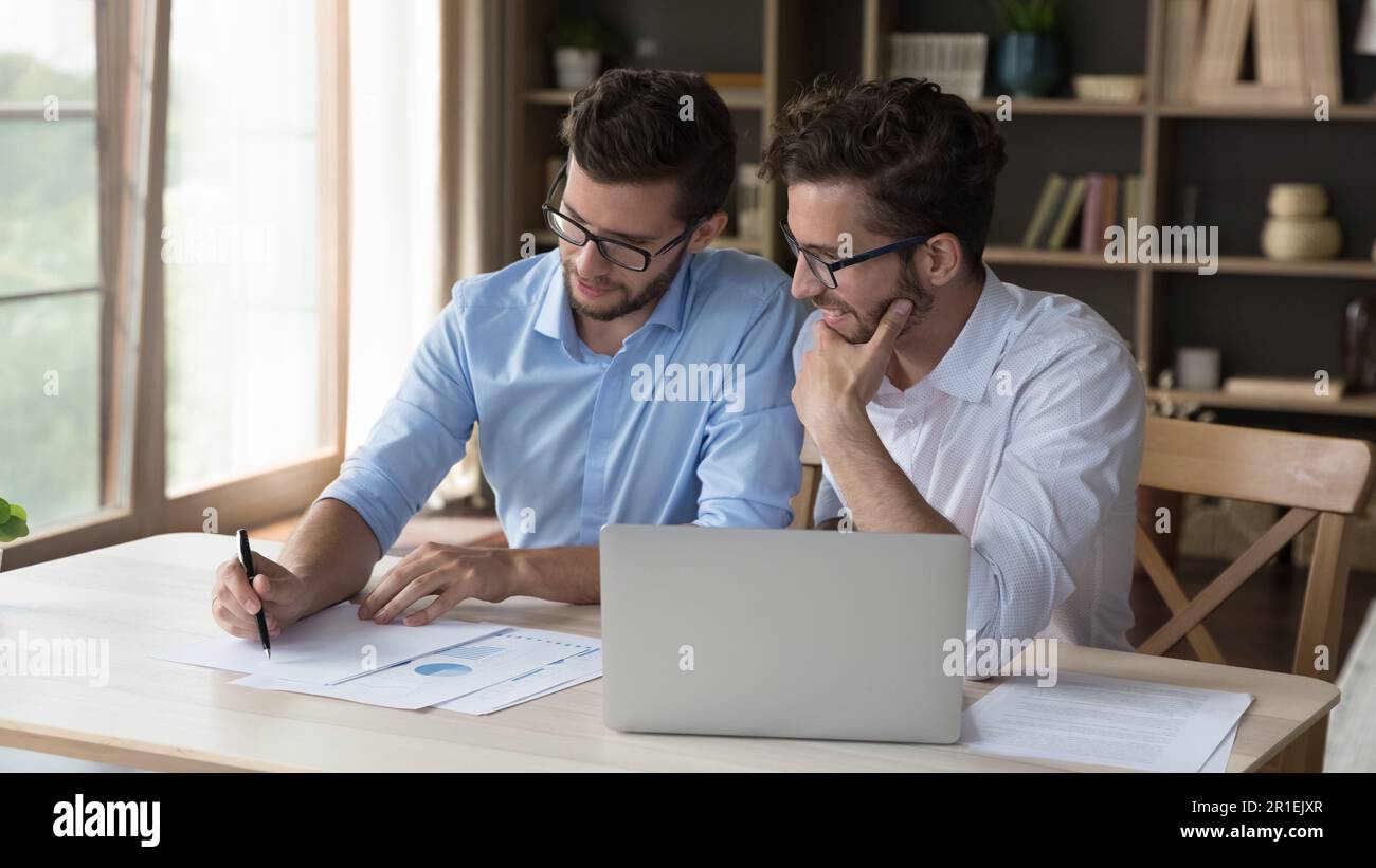 Positive engaged twin brothers working on family business project Stock ...
