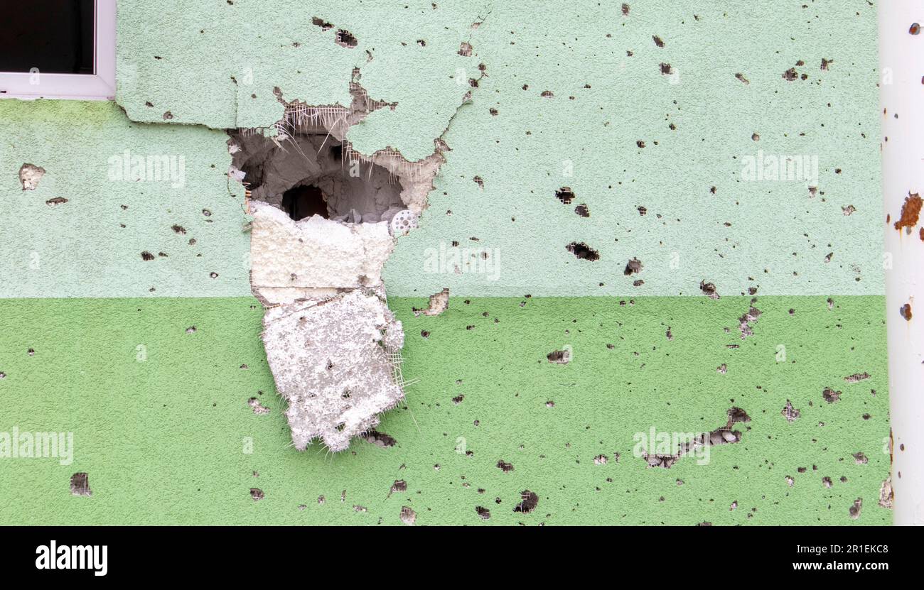 Holes from bullets and shrapnel in the wall on the front line. Scars of ...