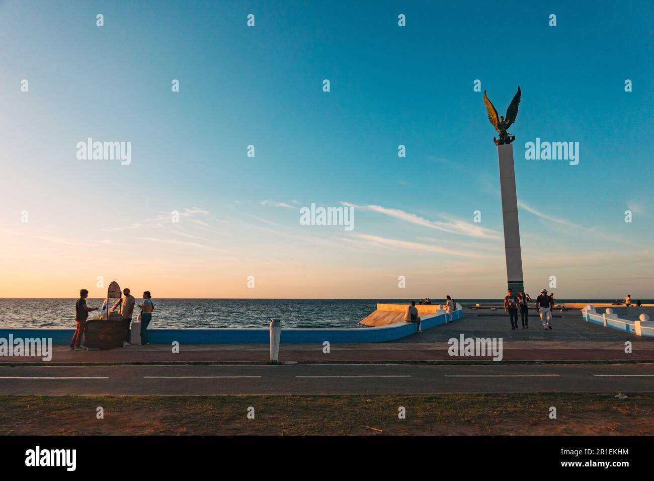residents relax along the malecón in front of The Mayan Angel sculpture ...