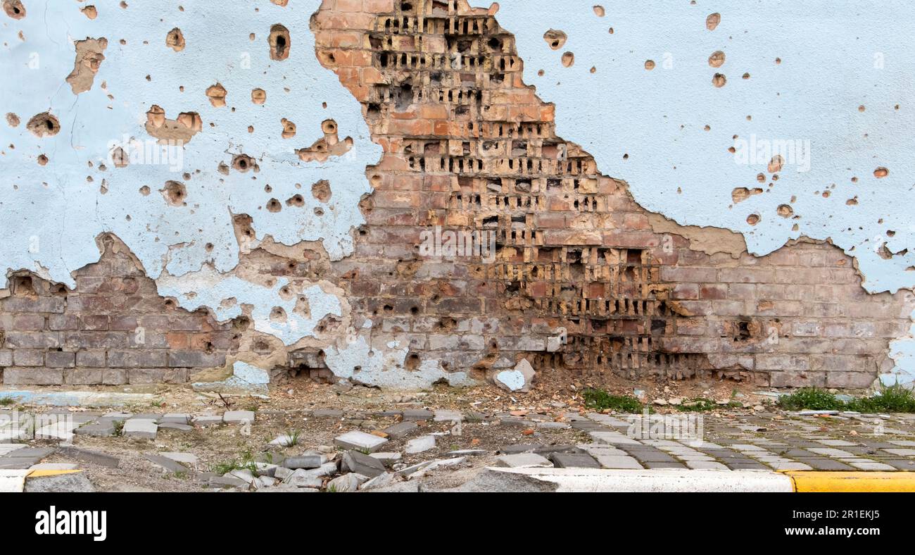 The wall of a building battered by rocket fragments in a war zone ...