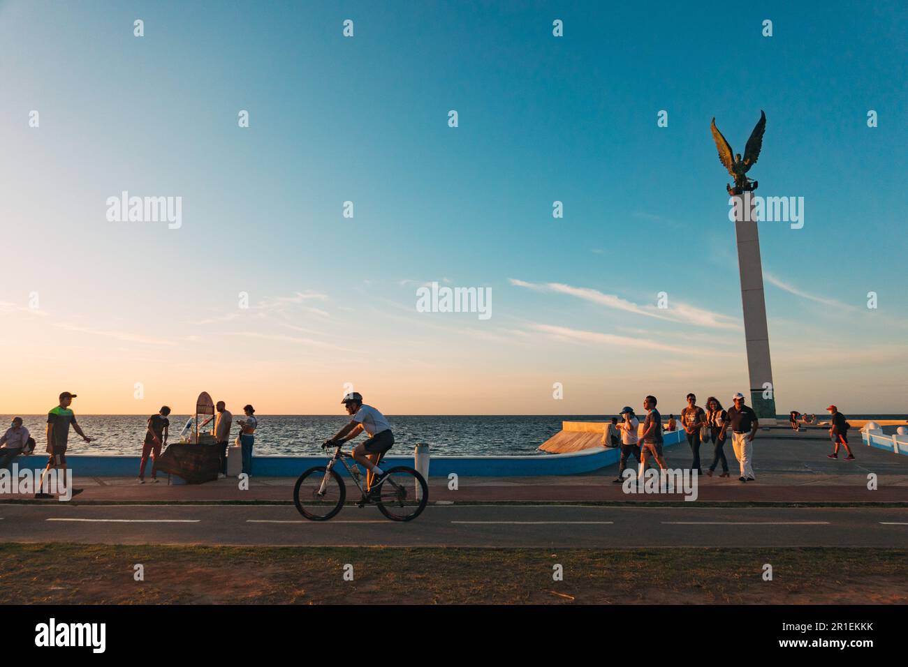 residents relax along the malecón in front of The Mayan Angel sculpture ...
