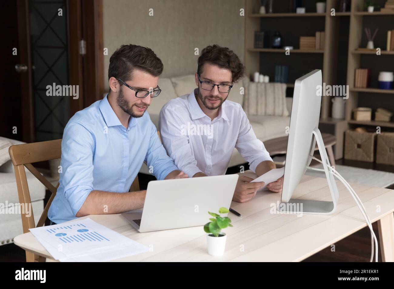 Positive handsome male twins cooperating on family business project ...
