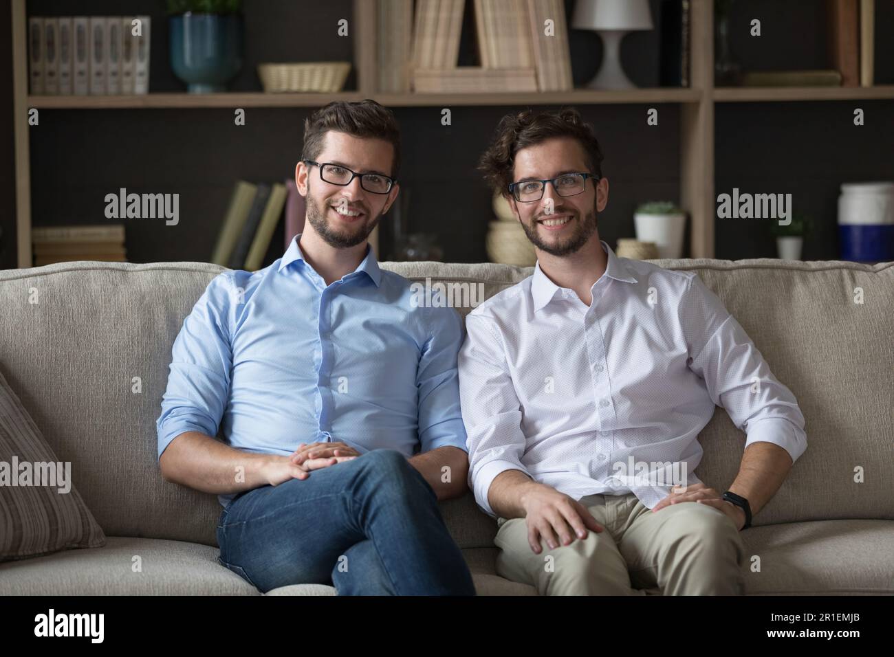 Happy positive young adult identical twin men sitting together Stock ...
