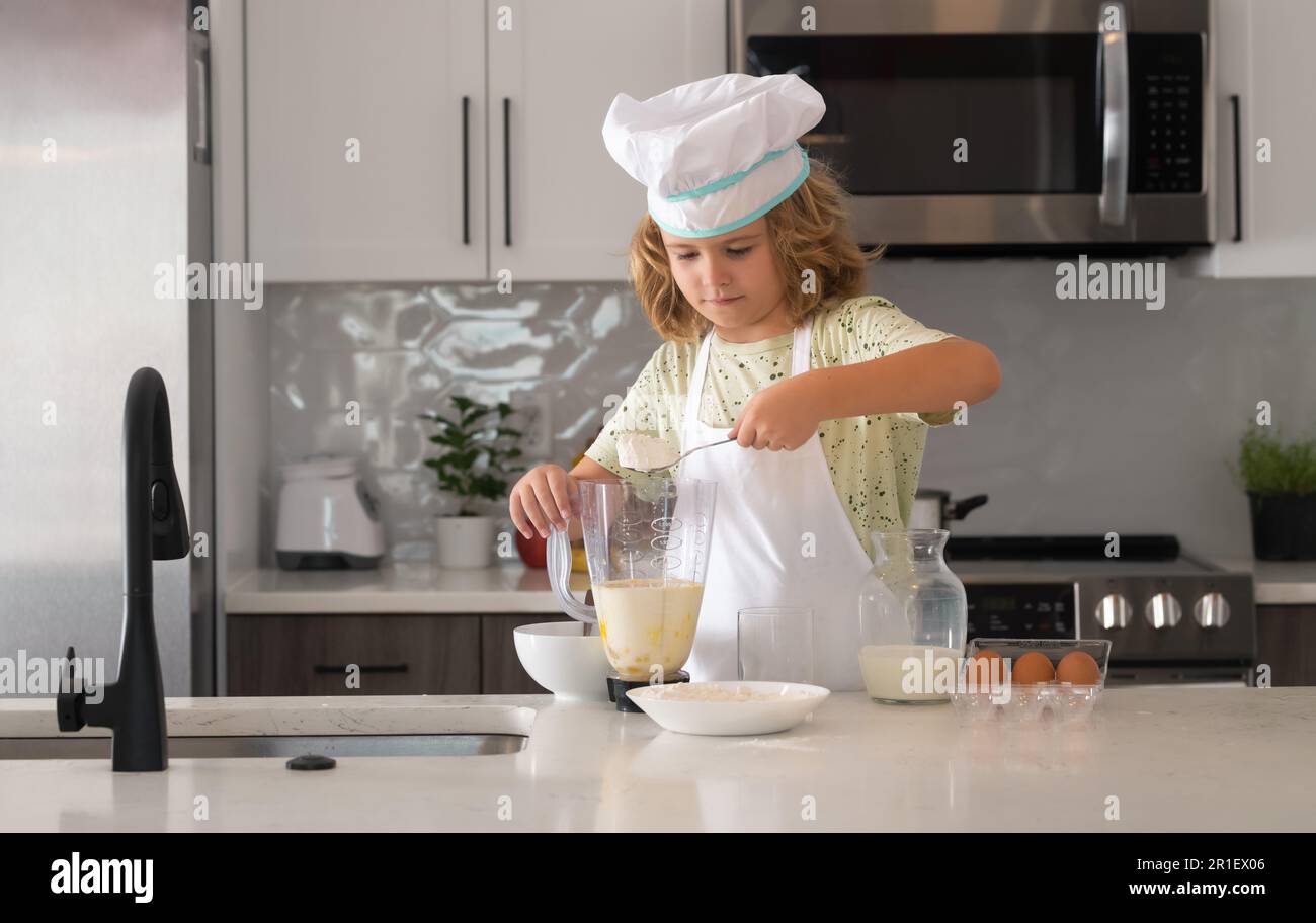 Chef kid boy baking on the kitchen. Child chef cook prepares food at ...