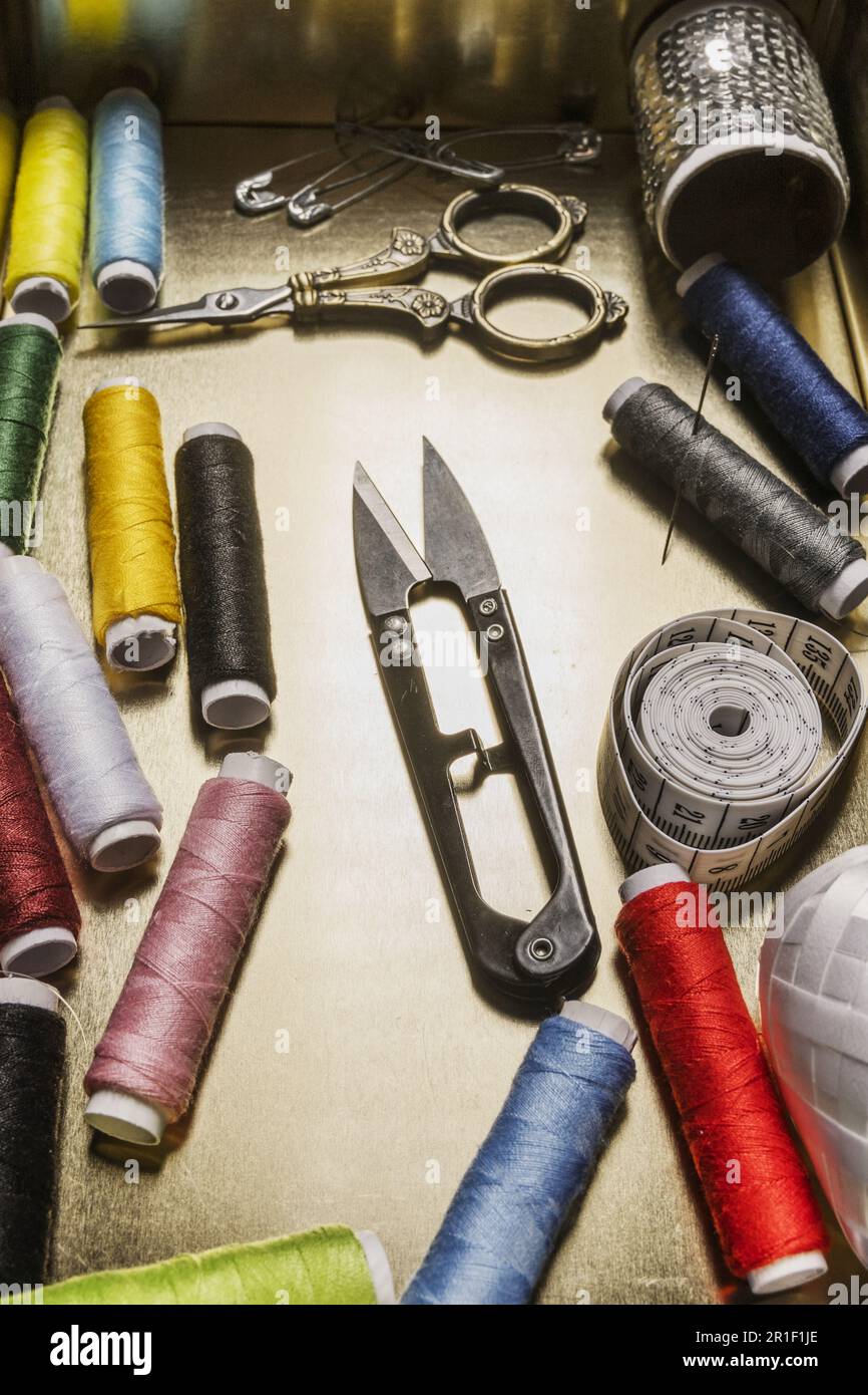 A tin full of sewing accessories with a tape measure and spools of ...