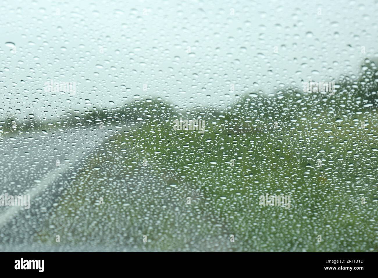 Blurred view of country road through wet car window. Rainy weather ...