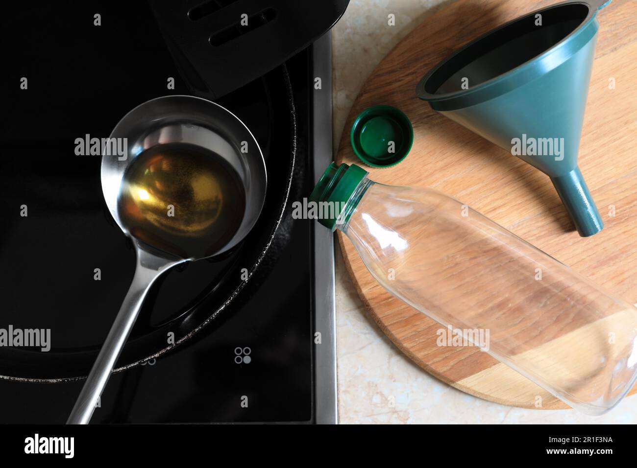 Frying pan of used cooking oil with ladle, empty bottle and funnel in ...