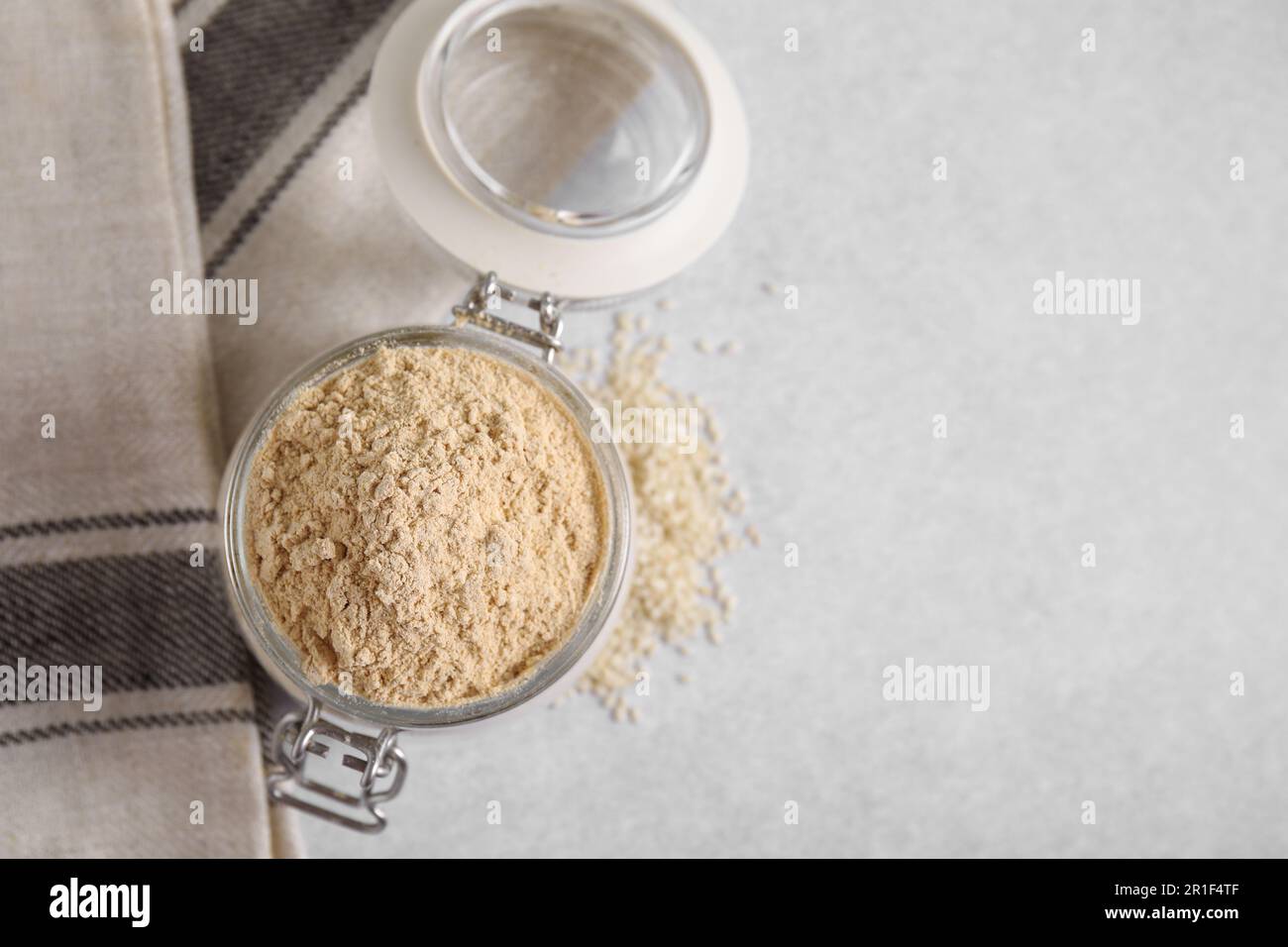 Sesame flour in glass jar on grey table, top view. Space for text Stock ...