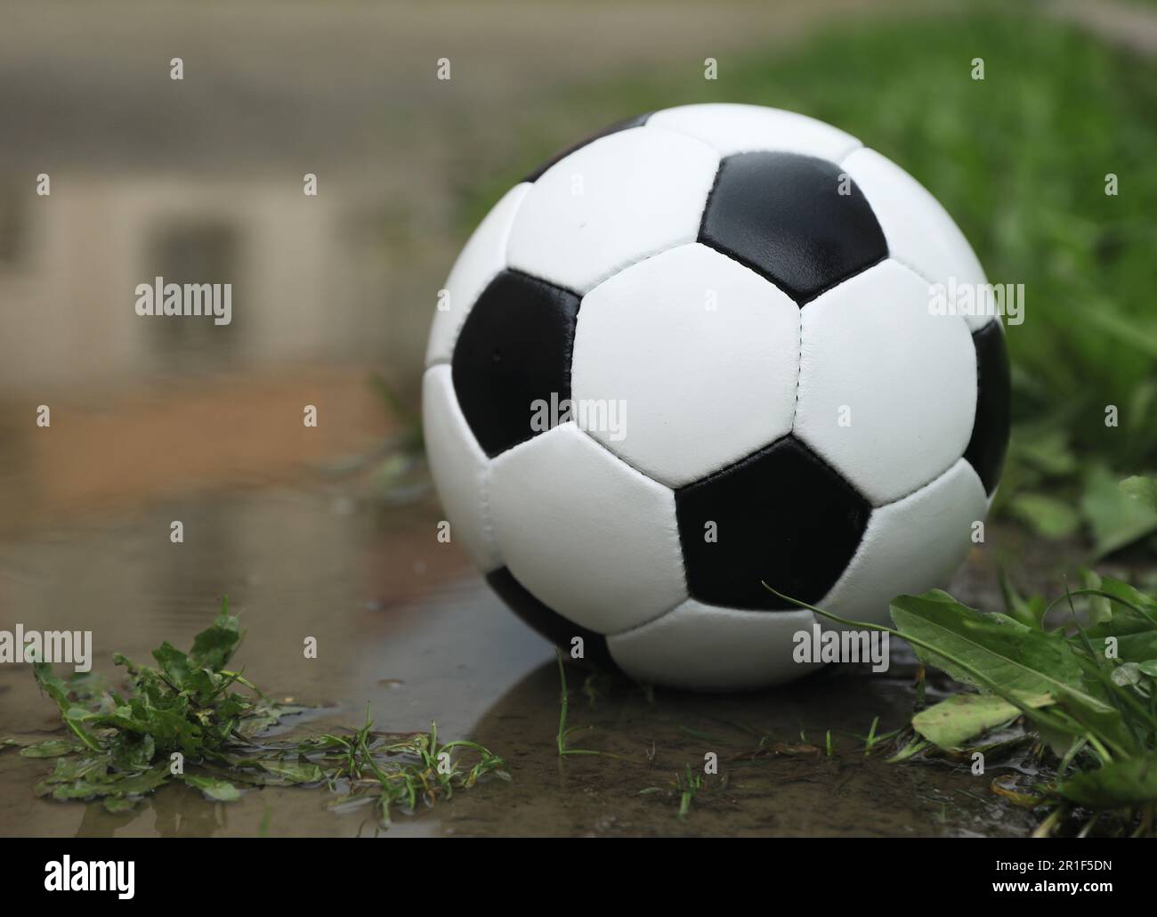 Soccer ball in puddle outdoors, space for text Stock Photo - Alamy