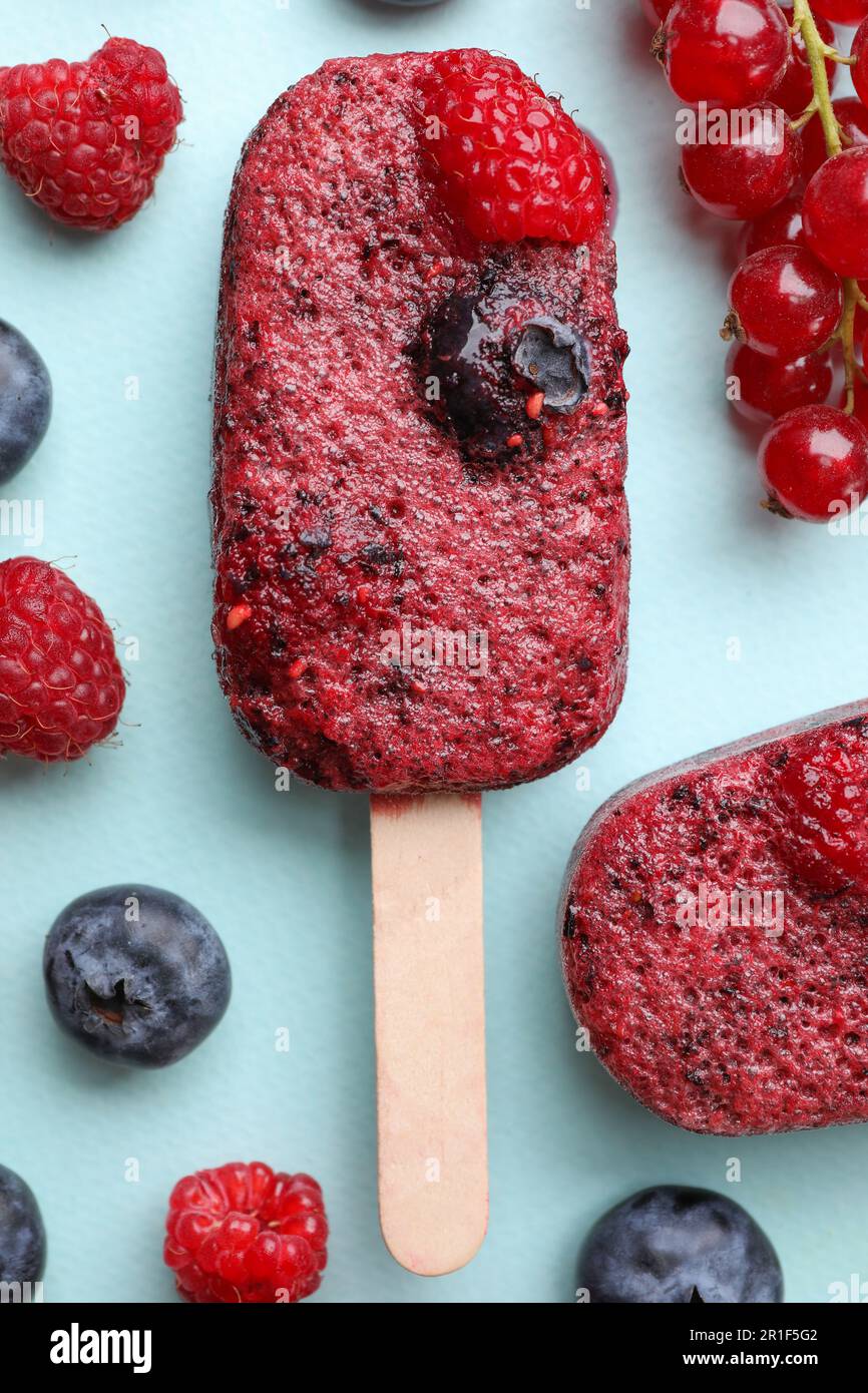 Tasty berry ice pops on light blue background, flat lay. Fruit popsicle ...