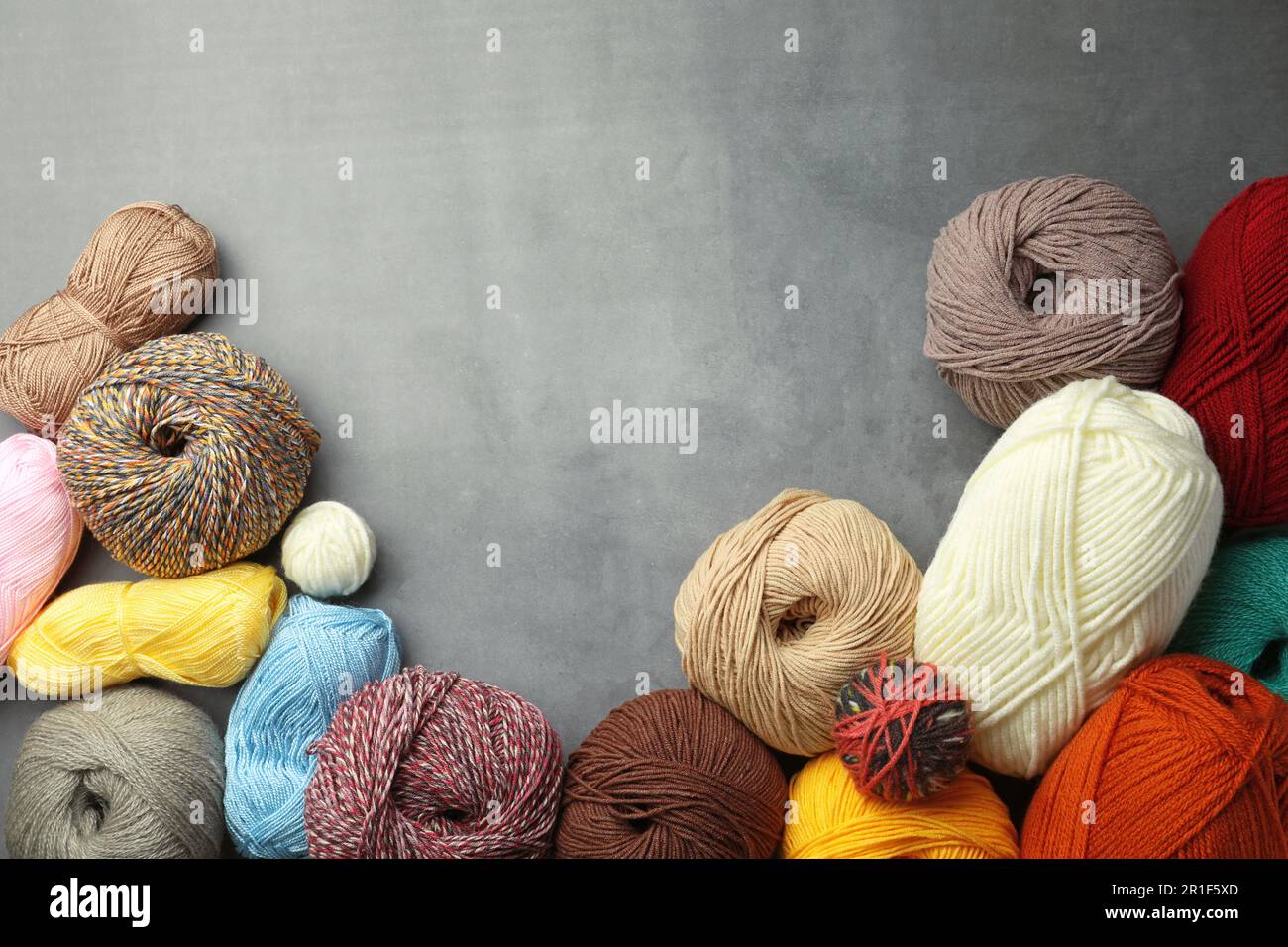 Different balls of woolen knitting yarns on grey background, flat lay ...