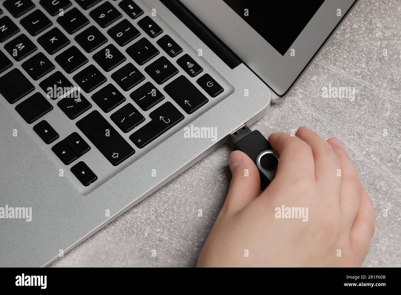 Woman attaching usb flash drive into laptop at grey table, closeup ...