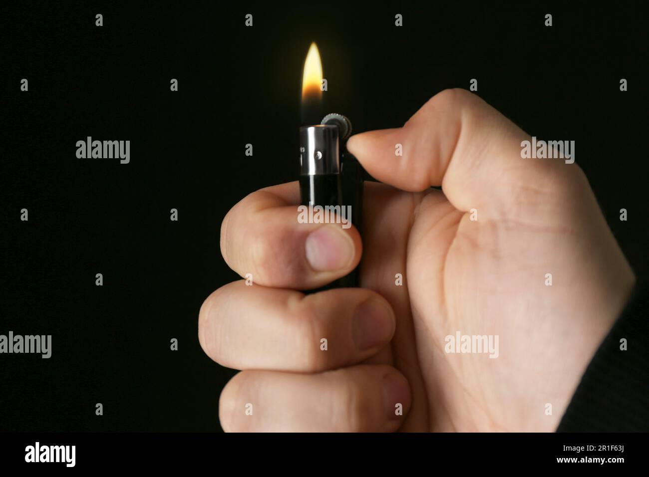 Man holding lighter on black background, closeup Stock Photo - Alamy