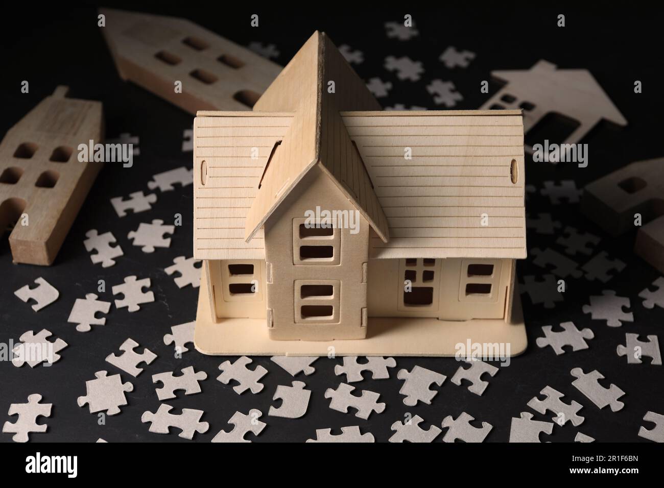 House model and puzzles on black table depicting destruction after ...