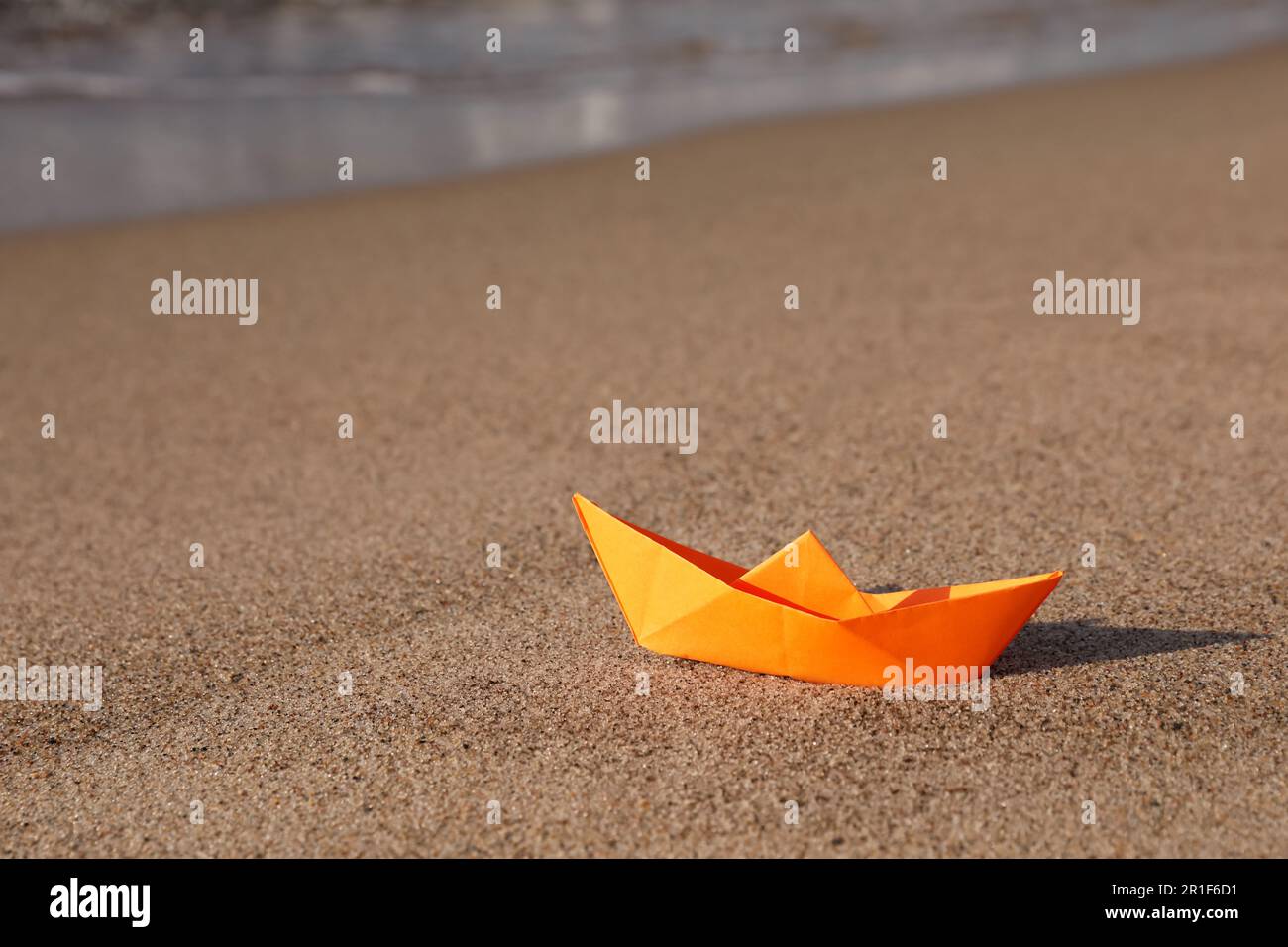 Orange paper boat on sand near sea, space for text Stock Photo - Alamy
