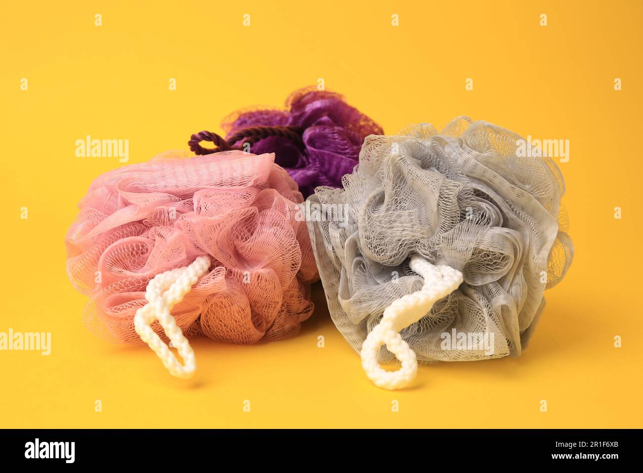 Colorful shower puffs on yellow background. Personal hygiene Stock ...