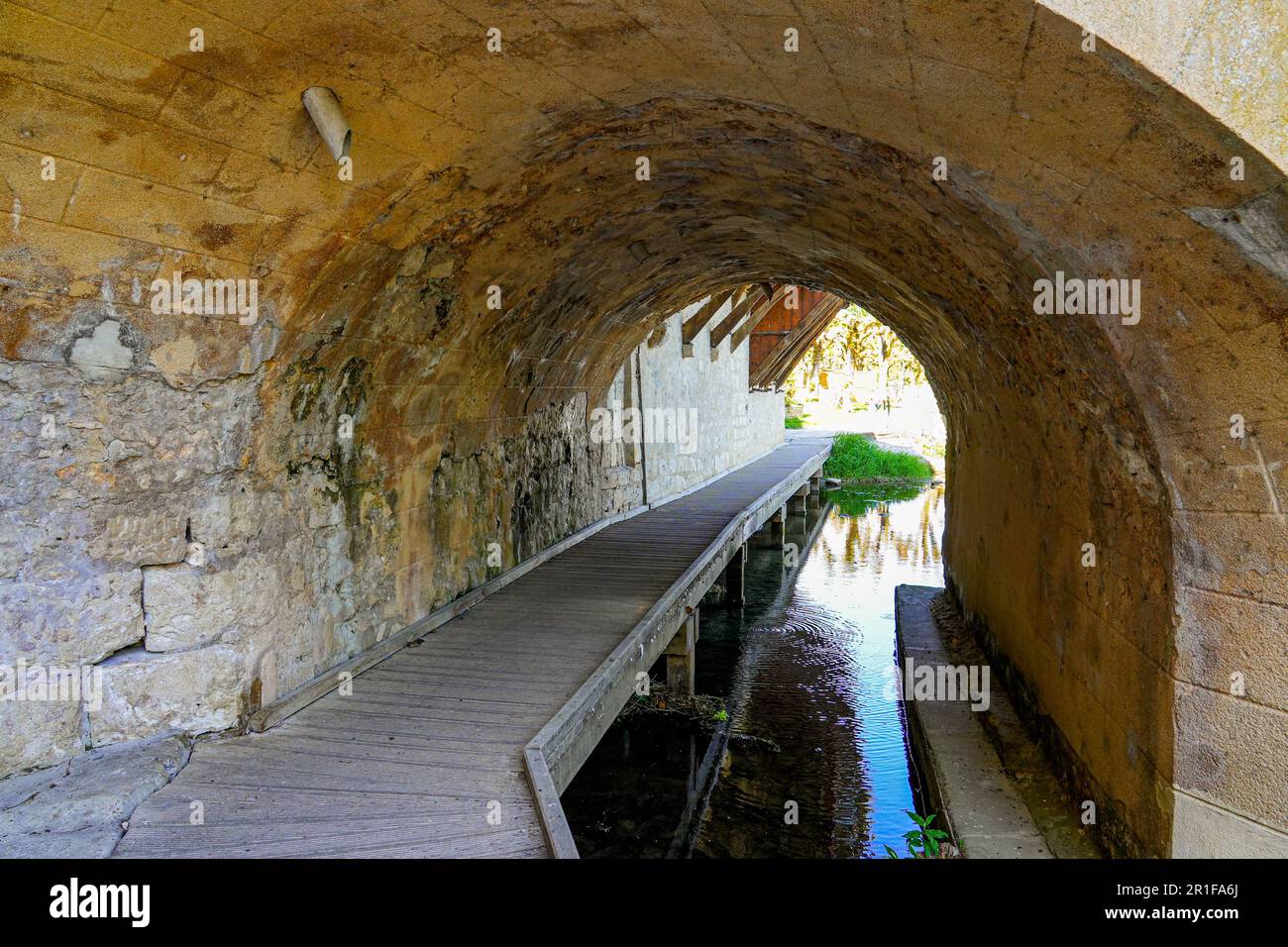 Boardwalk in the vaulted passage under the stone bridge spanning the ...