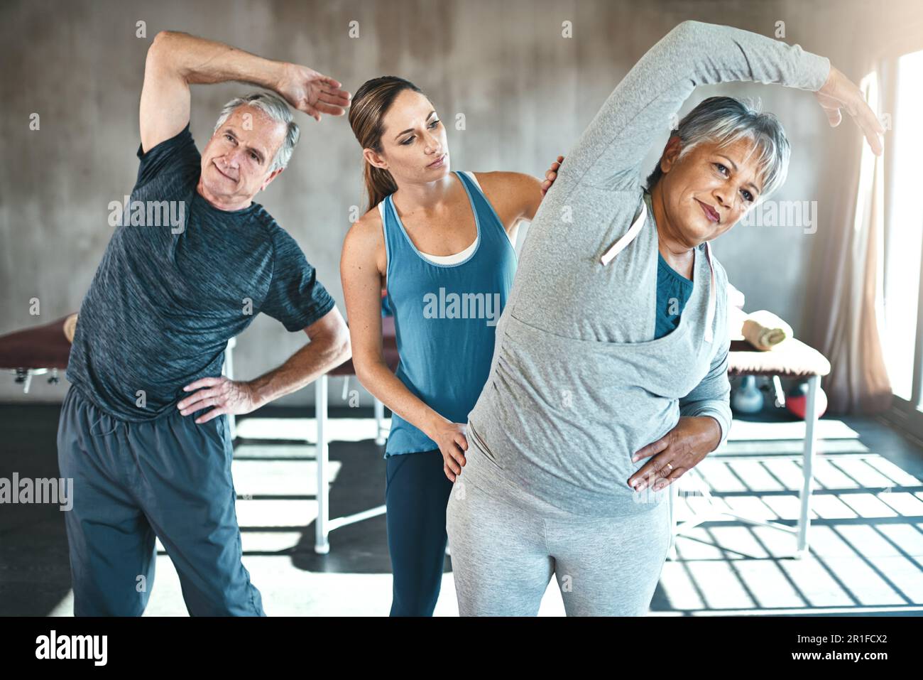 Stretching, helping and senior people with personal trainer in class ...