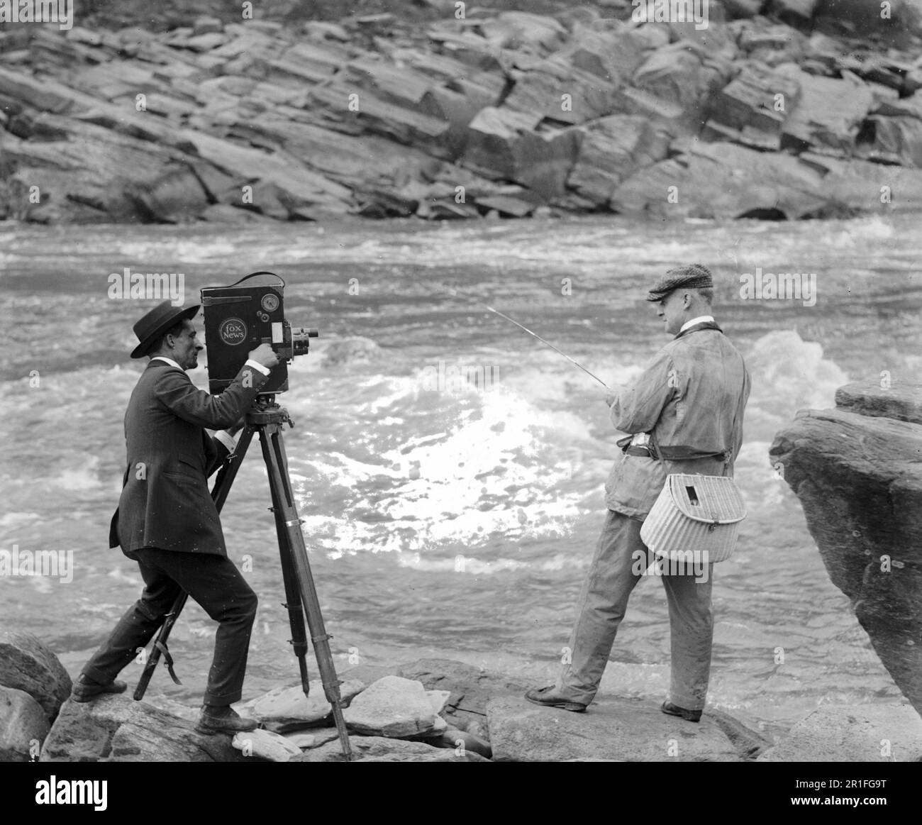 Archival Photo: A man with a film camera filming Senator Miles Poindexter fishing ca. 1918-1920 ...
