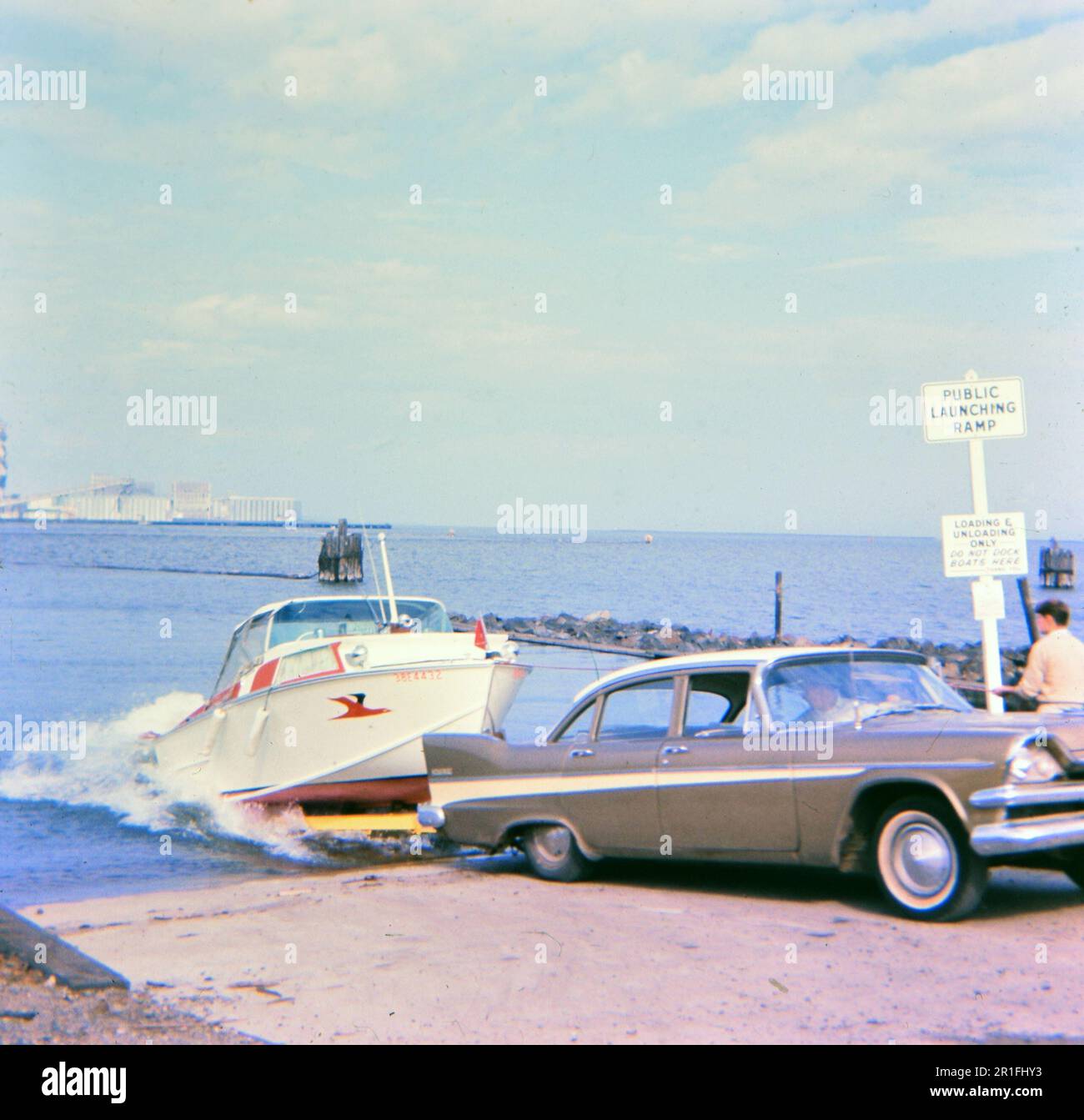 Man in a car at a boat ramp lowering his boat into the water ca. 1967 ...